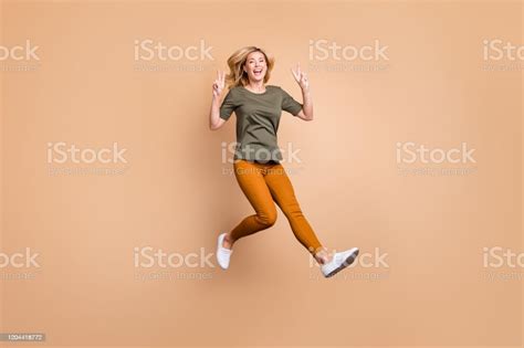 미친 여자 점프 높은 표시 V기호 말하는 안녕 친구 흥분 여름 분위기 착용 녹색 티셔츠 노란색 바지 고립 된 베이지 색 배경 브이에 대한 스톡 사진 및 기타 이미지 Istock