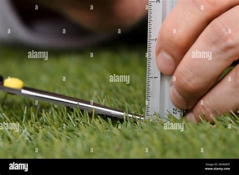 Close Up Of A Man Using Measuring Scale While Cutting Grass With