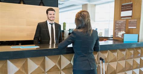 호텔 프론트 데스크에서 짐을 들고 서 있는 사업가를 보면서 웃고 있는 잘생긴 중년 매니저 사진 Unsplash의 사람 이미지