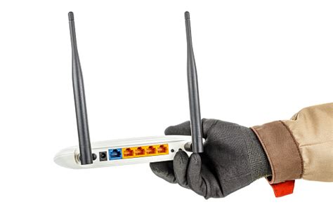 블랙 보호 장갑과 흰색 배경에 고립 된 갈색 유니폼을 입은 남자 손에 있는 뒷면 패널에 컬러 연결 포트가있는 무선 Wifi 라우터 It 지원에 대한 스톡 사진 및 기타