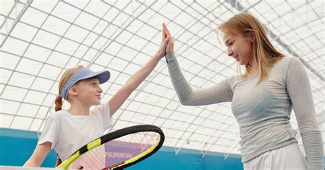 현대 경기장에서 성공적인 경기를 한 후 네트를 통해 트레이너에게 하이파이브를 하면서 테니스 라켓을 들고 활동복을 입은 행복한 십 대 소녀 사진 Unsplash의 라켓 이미지