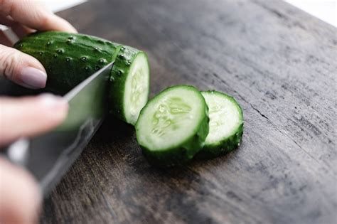 Premium Photo Close Up Of Woman Hand Cutting Cucumber On Chopping Wood Board With Sharp Knife