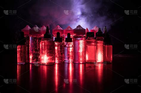 Vape概念。黑色背景上的烟雾和电子烟液体瓶。光的效果
