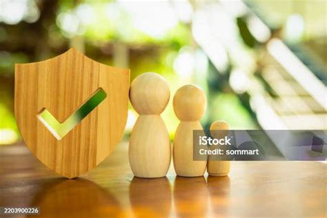 방패와 체크 표시가 있는 보험 기호는 가족의 나무 모델 그룹 보험의 개념 가족 건강 및 생명 보험과 함께 테이블에 놓여 있습니다