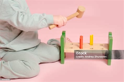 행복 한 유아 아기는 스튜디오 분홍색 배경에 망치와 나무 손톱을 가지고 놀고 있습니다 교육 장난감을 가진 아이 소년 아이 나이 1 년 8 개월 18 23 개월에 대한 스톡