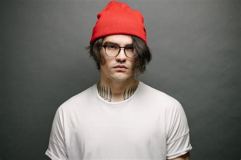 흰색 공백 T 셔츠와 빨간 바지와 회색 배경 위에 로고 또는 디자인을위한 공간을 가진 빨간 모자를 쓰고 안경 소식통 잘 생긴 남성 모델 프리미엄 사진