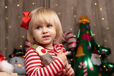 Little Two Year Old Girl Eating Lollipop At Christmas While Sitting At