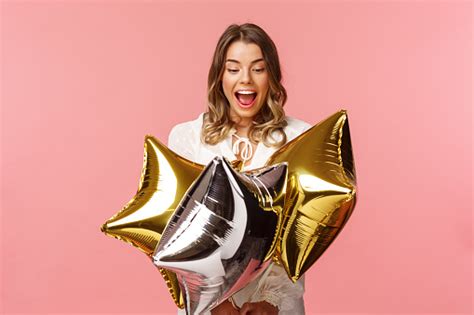 휴일 축 하 및 여성 개념입니다 흰색 드레스에 즐거운 아름다운 금발 소녀의 초상화는 분홍색 배경을 통해 파티 멋진 시작 모양의 풍선에 흥분하고 감동되고 고객에 대한 스톡