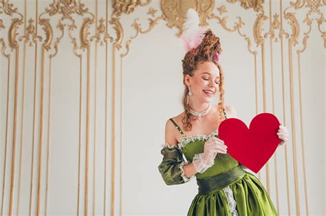 바로크 양식의 녹색 드레스를 입은 우아한 여성이 고급스러운 골동품 인테리어에 장식용 빨간 심장을 들고 있습니다 20 24세에 대한 스톡 사진 및 기타 이미지 Istock