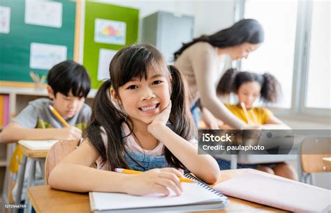 초등학교 교실 책상에서 쓰는 미소 어린 학생의 초상화 초등학교에서 시험을 하고 있는 학생 소녀 아이들은 교실에서 메모를 작성합니다 교육 지식 개념 교육에 대한 스톡 사진 및