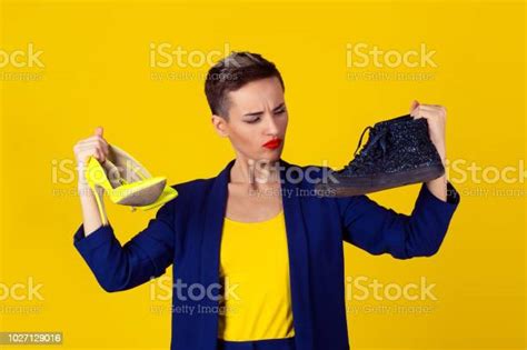 여 자가 얼굴에 높은 발뒤꿈치와 혼란 스러운된 표정으로 한 플랫 슈즈 한 켤레를 들고 비교에 대한 스톡 사진 및 기타 이미지 비교 생활필수품 스포츠 신발 Istock