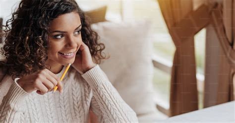 감동적인 분위기 미소는 영감을 받은 아프리카계 미국인 여성이 카페에 앉아 소설을 쓰는 동안 담요로 덮인 것과 관련이 있습니다 사진 Unsplash의 기쁨 이미지