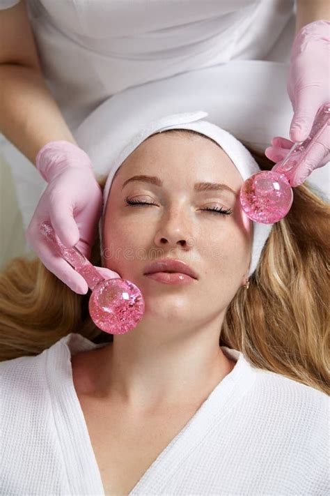 Young Woman Receiving Facial Massage With Glass Balls In Beauty Salon