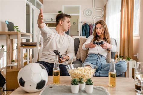 두 백인 사람들이 집에서 재생 비디오 게임 콘솔 데 재미 젊은 부부 남자와 여자 남자 친구와 여자 친구 함께 조이스틱 컨트롤러 웃는 전면 보기를 들고 시간을 보내고 16