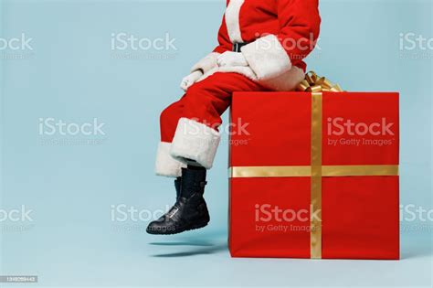 평범한 파란색 배경 스튜디오에서 고립 된 큰 선물 선물 상자에 앉아있는 크리스마스 빨간 정장 옷을 입은 오래된 산타 클로스