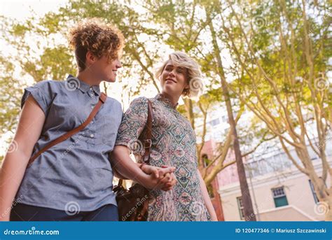 Smiling Lesbian Couple Holding Hands While Walking In The City Stock
