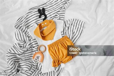 하얀 장난꾸러기 오렌지색 반바지 및 아기 장난감이있는 턱받이 침대에서 여름을위한 어린이 옷과 액세서리 세트 패션 아이 복장 플랫 레이 상단 뷰 0명에 대한 스톡 사진 및
