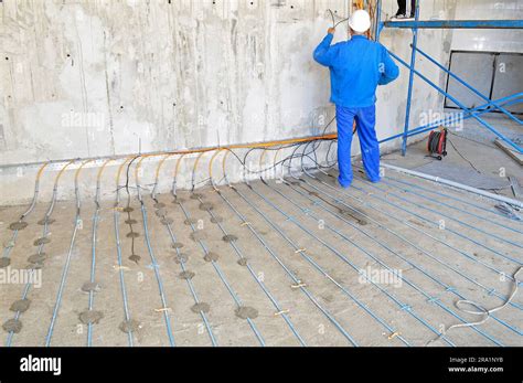 A Man Wearing A Blue Uniform Is Seen Installing An Underfloor Heating