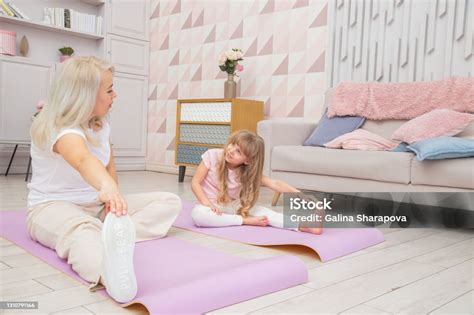 전체 길이 전면 보기 귀여운 장난 작은 유치원 딸과 요가 매트에 금발 어머니를 미소 다양한 운동을합니다 어린 아이와 함께 운동