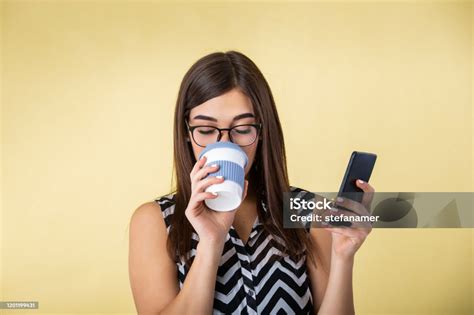 복숭아 배경으로 고립 된 스마트 폰을 들고 뜨거운 음료와 커피를 마시는 쾌활한 청소년의 초상화 커피 컵과 휴대 전화를 빼앗아 미소 소녀 기원에 대한 스톡 사진 및 기타