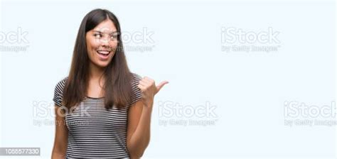 젊은 아름 다운 스페인 여자 생기고 엄지 측면 가리키는 행복 한 얼굴로 웃 고 가리키기에 대한 스톡 사진 및 기타 이미지 가리키기 한 명의 여자만 갈색 머리 Istock