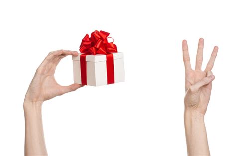 축 하와 선물의 테마 화이트 레드 리본 및 활 스튜디오에서 흰색 배경에 고립 된 가장 아름 다운 선물 상자에 포장 하는 선물을 들고 손 기념일에 대한 스톡 사진 및 기타