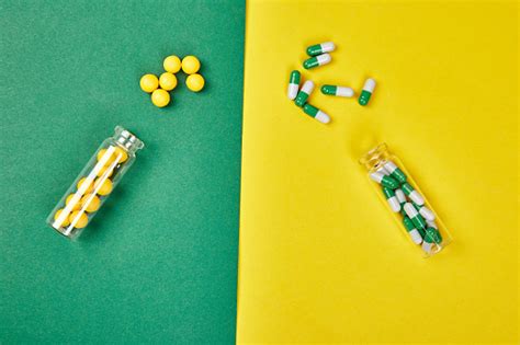의료 블로그에 대한 미니멀리즘 스타일의 템플릿 작은 유리 병 작은 노란색과 녹색 알약 종이 배경 밖으로 유출 제약 개념 약 알 약 플랫 레이 0명에 대한 스톡 사진 및 기타