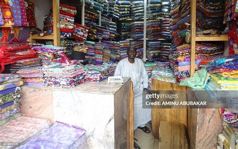 A Textile Trader Waits For Customers In His Shop In Kantin Kwati