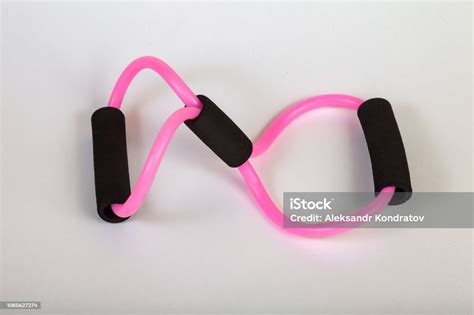 백색 격리 된 배경에 무한대 기호 형태로 손으로 피트 니스 연습을 수행 하기 위한 검은 Paralon 핸들 분홍색 고무 튜브 익 스팬 더 8에 대한 스톡 사진 및 기타