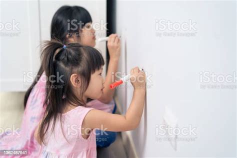 아시아의 젊은 형제 아이 소녀는 거실에서 흰색 벽에 페인트를 즐길 수 있습니다 재미있는 그림을 그리고 합창으로 예술 사진을