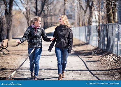 Duas Mulheres Loiras Andando Com Um Cachorro Foto De Stock Imagem De Engrenagem Fofofo
