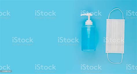 복사 공간이있는 밝은 파란색 배경의 상단보기 의료 용 얼굴 마스크 및 알코올 젤 펌프 헤드 병에 얼굴 마스크와 손 소독제 젤 0