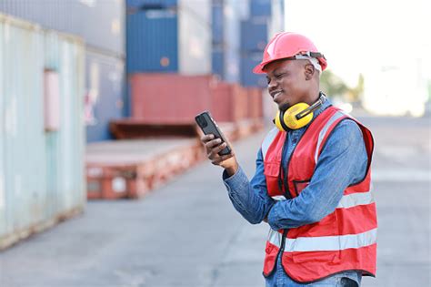 감독은 스마트 휴대 전화를 사용하여 컨테이너 상자 적재를 제어합니다 안전모를 쓴 엔지니어 또는 작업자는 컨테이너 화물 현장에서