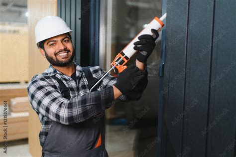 Indian Worker Is Applying Polyurethane Foam To Fill Gap Between Sash And Window Frame In