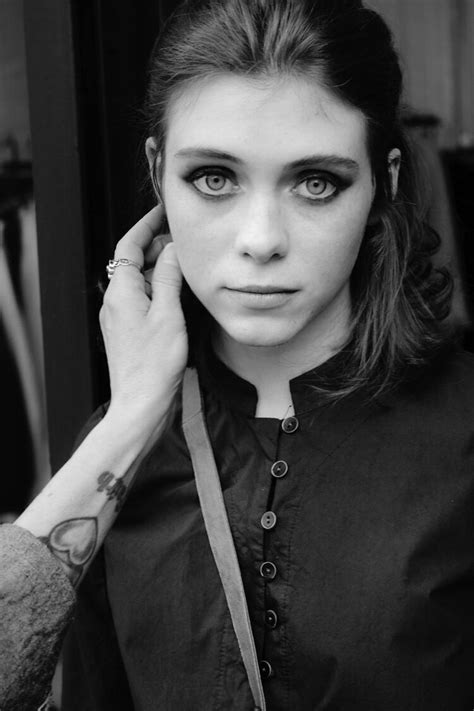 A Woman Is Posing For The Camera With Her Hand On Her Ear And Looking