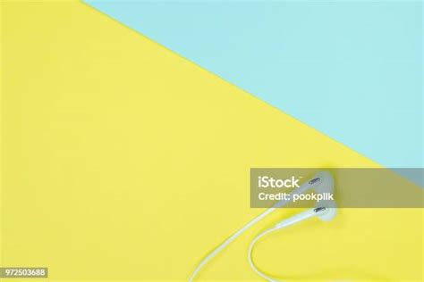 화이트 이어폰 또는 귀에 달콤한 파란색과 노란색 컬러 파스텔 종이 평면도 텍스처 및 배경 잡담에 꽃 봉 오리 음악 듣기