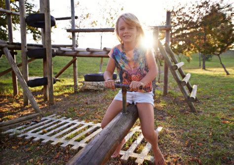 Happy Girl Portrait And Riding Seesaw In Park Sunset For Fun Holiday