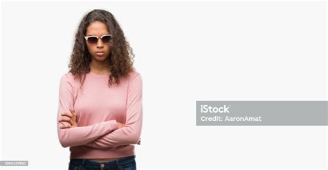아름 다운 젊은 히스패닉 여자 선글라스 의심과 긴장 Disapproving 식 교차 팔과 얼굴에 착용 부정적인 사람입니다 갈색 머리에 대한 스톡 사진 및 기타 이미지