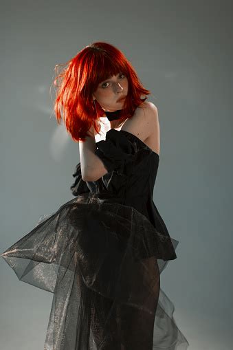 멋진 빨간 머리 여자 창백한 피부와 검은 드레스를 입은 붉은 머리를 가진 고딕 양식의 여성 스튜디오에서 목에 목걸이를 신는다