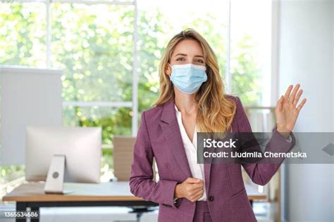 사무실에서 헬로 제스처를 보여주는 보호 마스크를 입은 여성 코로나바이러스 전염병 중 사회적 거리 유지 25 29세에 대한 스톡 사진 및 기타 이미지 Istock
