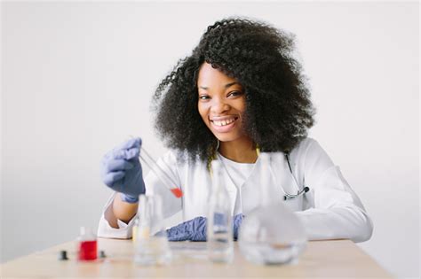 청진기와 흰색 코트에 젊은 아름다운 아프리카 계 미국인 소녀 의사 흰색 배경에 시약 플라스크와 테이블에 앉아 조사관검사시험관 Stem 주제에 대한 스톡 사진 및 기타 이미지