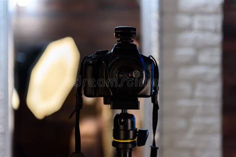 Professional Digital Camera On A Tripod Connected By A Synchronizer To The Flashlights At Home