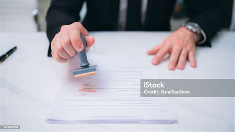 사업가는 배경에 계약서 용지가 있는 테이블에서 텍스트 문서에 승인된 스탬프를 손으로 찍고 있습니다 경영자에 대한 스톡 사진 및 기타 이미지 Istock
