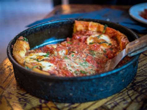 Delicious And Famous Chicago Style Deep Dish Pizza In Its Cooking Pan On Wooden Table Stock