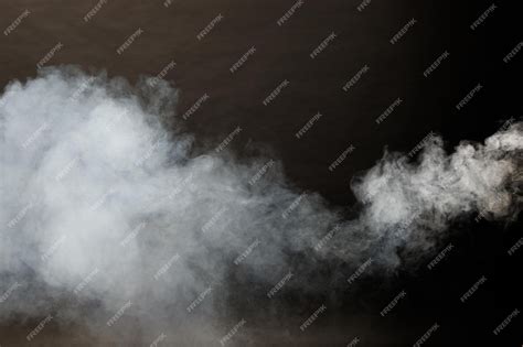 검은 배경에 흰 연기와 안개의 짙은 솜털 퍼프 추상 연기 구름 초점이 흐릿한 움직임 기계 드라이아이스의 연기가 날리고 공기