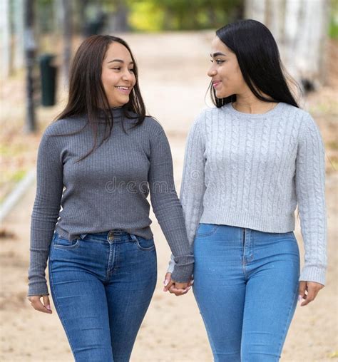 Portrait Of Happy Lesbian Girls Holding Hands And Walking In A Park