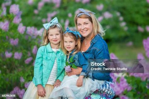 어머니 여자 두 귀여운 웃는 여자 자매 사랑 스러운 함께 라일락 필드에 모두 입고 세련 된 드레스와 청바지 코트 부시 3 명에 대한 스톡 사진 및 기타 이미지 Istock
