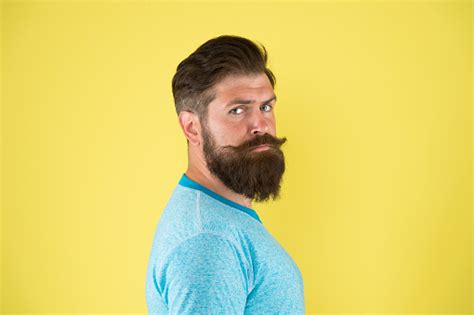 콧수염을 키우기 수염을 기고 한 힙스터를 수염으로 수염을 기릅니다 수염과 콧수염 그루밍 가이드 힙스터 잘 생긴 수염 매력적인 남자 노란색 배경 이발소 컨셉 콧수염 의 성장과