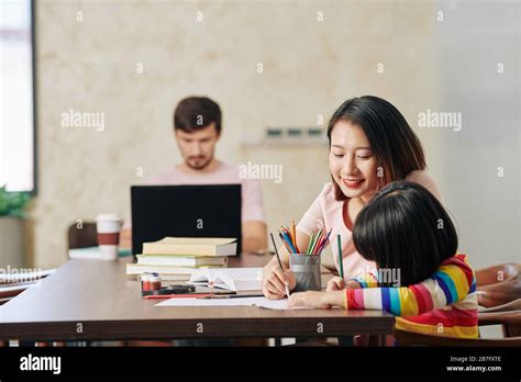 Fröhliche junge Vietnamesin hilft ihrer kleinen Tochter beim Zeichnen Stockfotografie Alamy