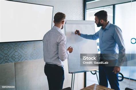 남성 건축가의 뒷모습은 화이트 보드를 사용하여 아이디어를 공유하고 사무실 내부에서 브리핑 및 회의에 대해 논의하고 전략 창작